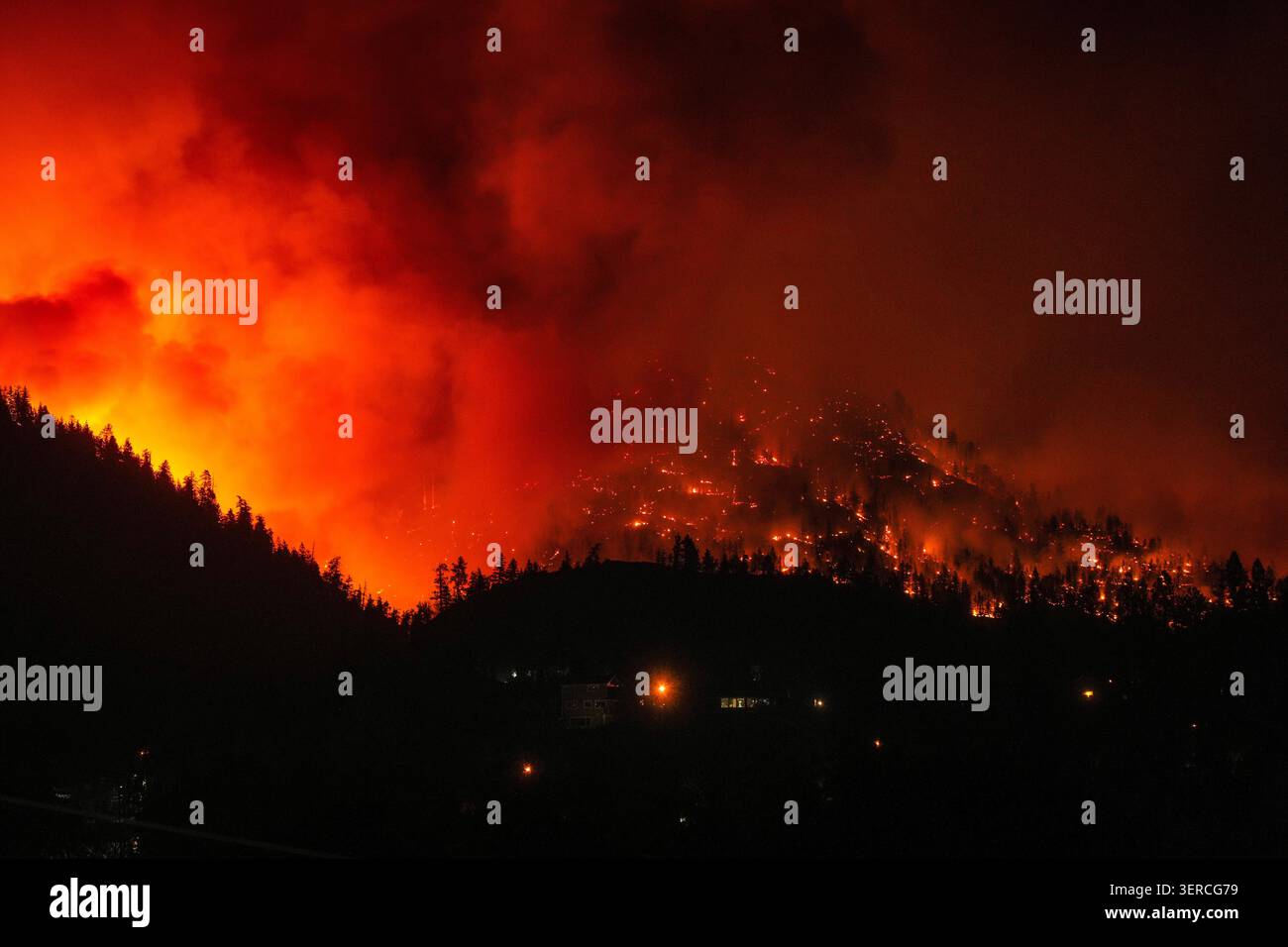 The McDougall Creek wildfire burns on the mountainside above houses in ...