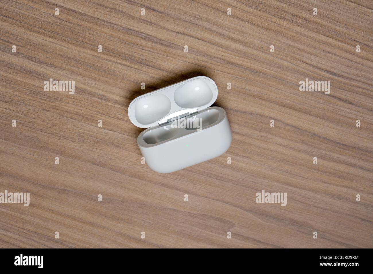 White earbud case rests open on wooden surface. Clean design ...