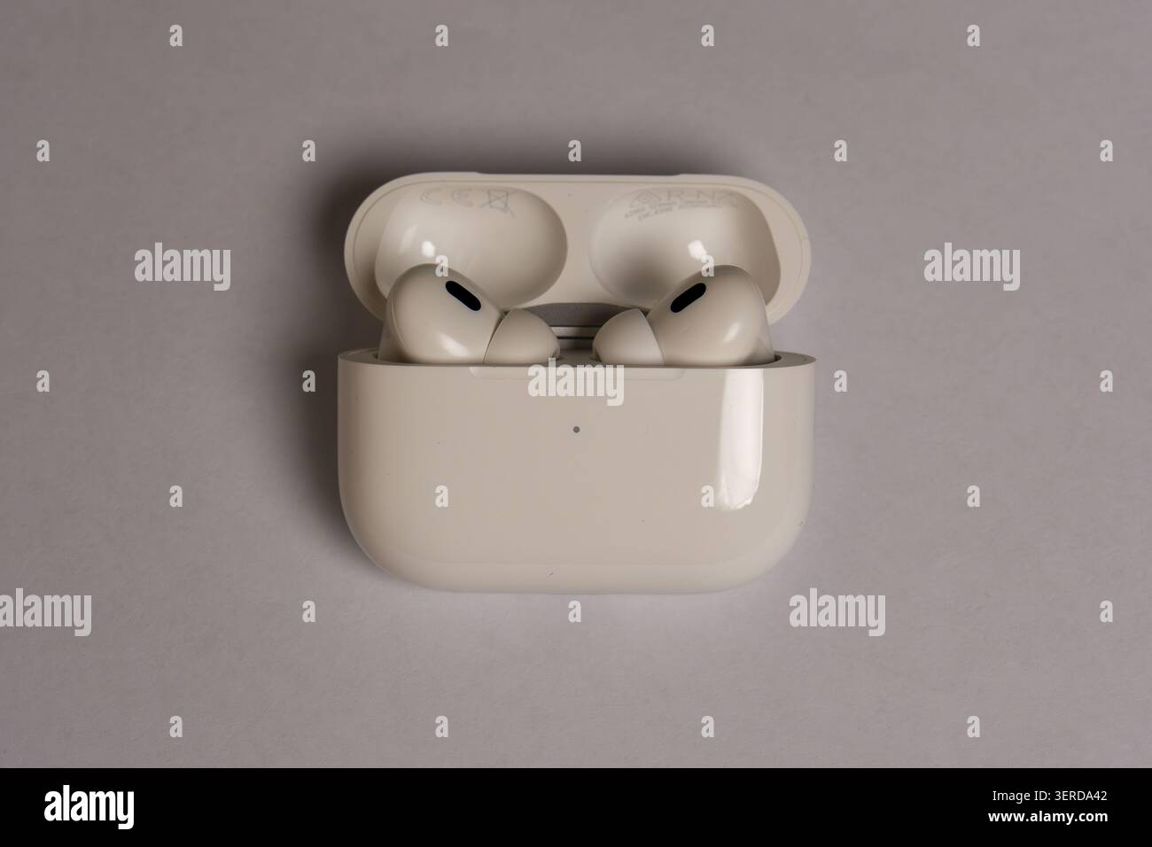 White earbuds rest in open charging case. Minimalist design with clean ...