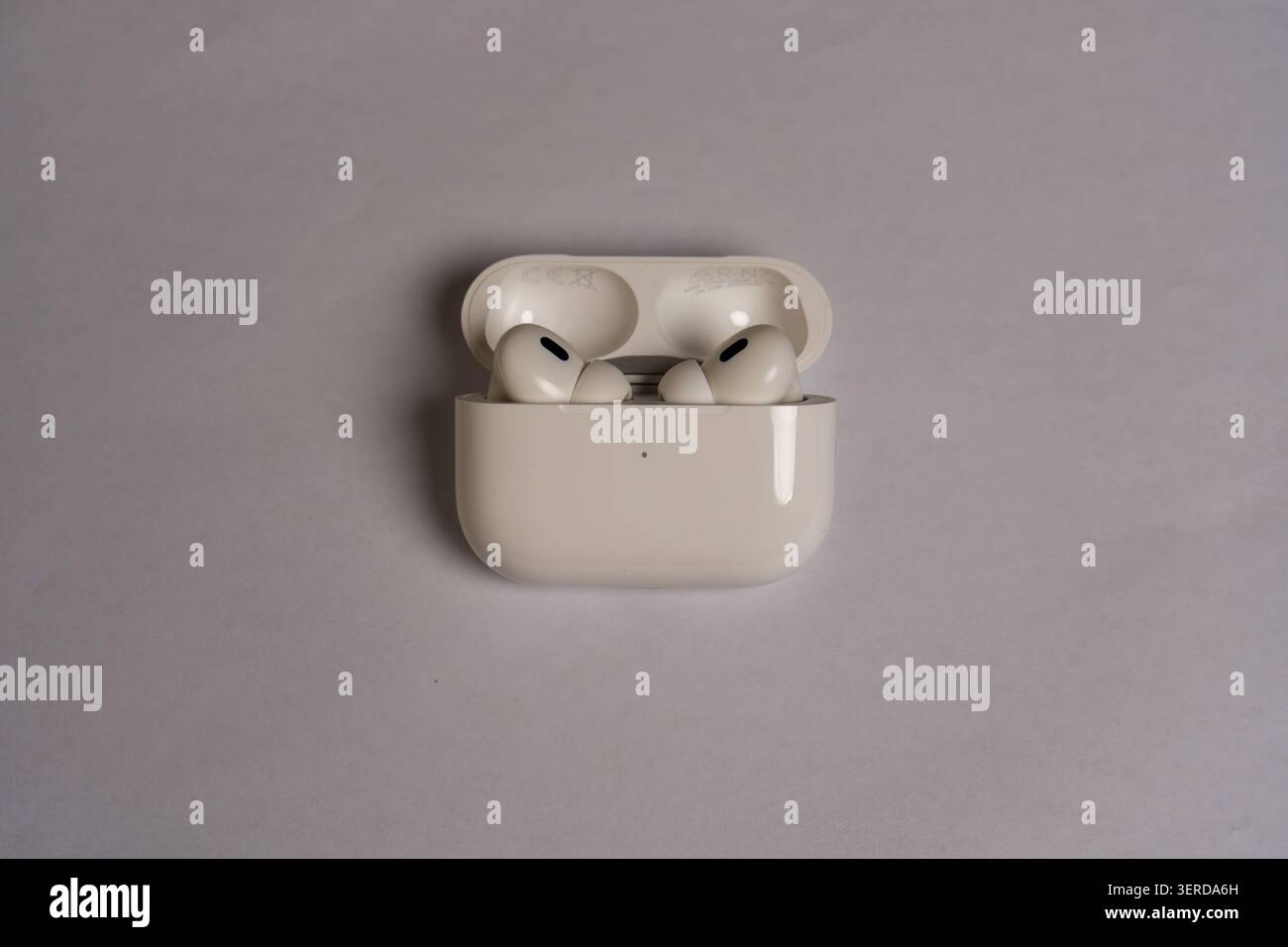 White earbuds rest in open charging case. Simple background highlights ...