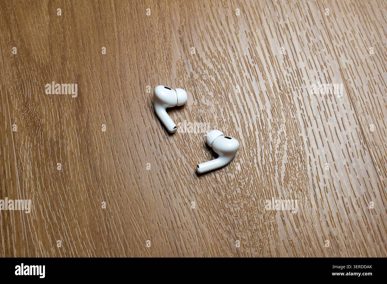 White wireless earbuds rest on a wooden surface. Simple design, clean ...