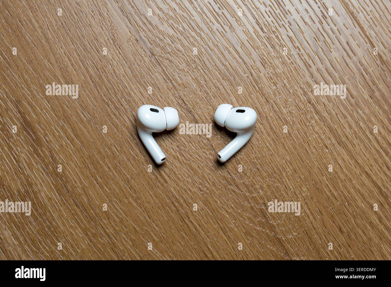 White earbuds rest on a wooden surface. Simple, clean composition ...