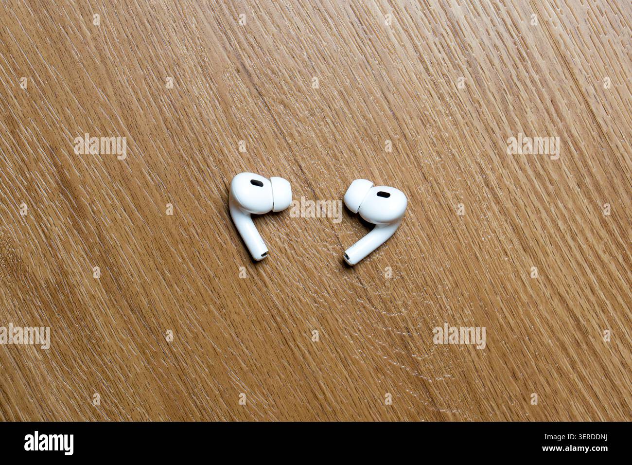 White earbuds rest on a wooden surface. Simple, clean design against ...