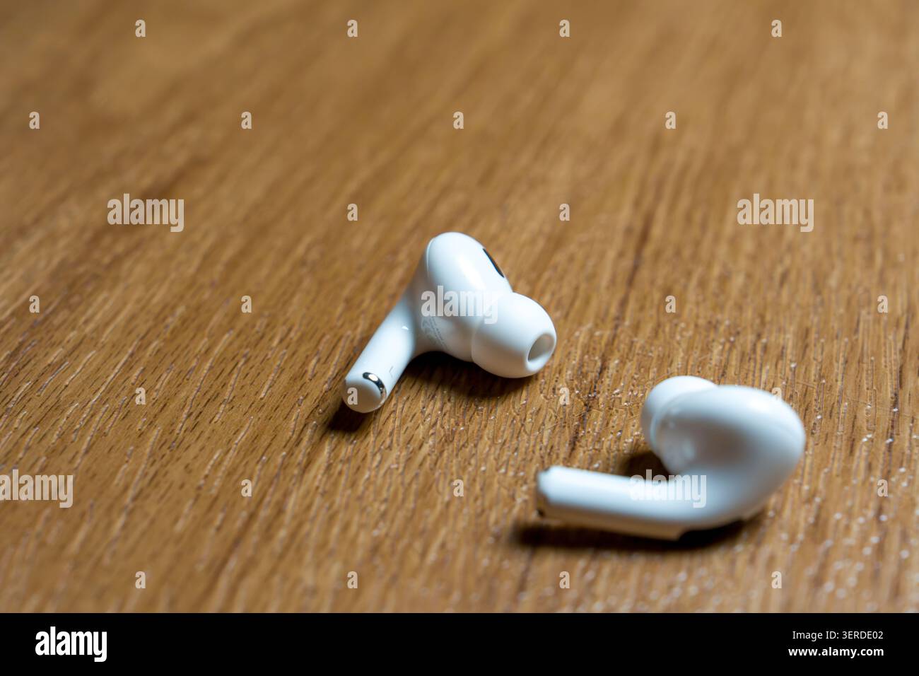 White earbuds rest on wooden surface. Soft focus highlights smooth ...