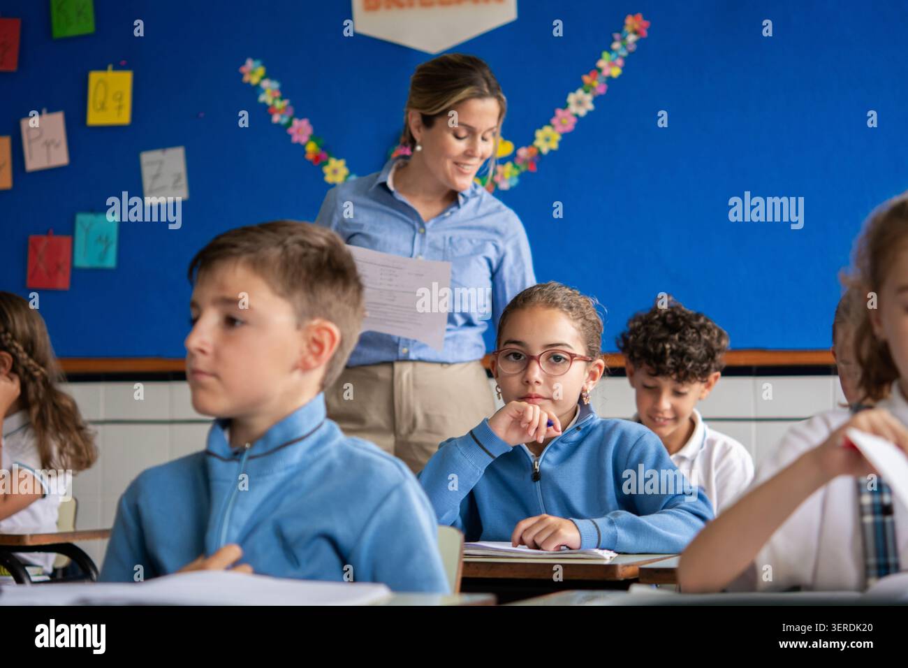 Primary school student reviewing worksheets and completing classroom ...