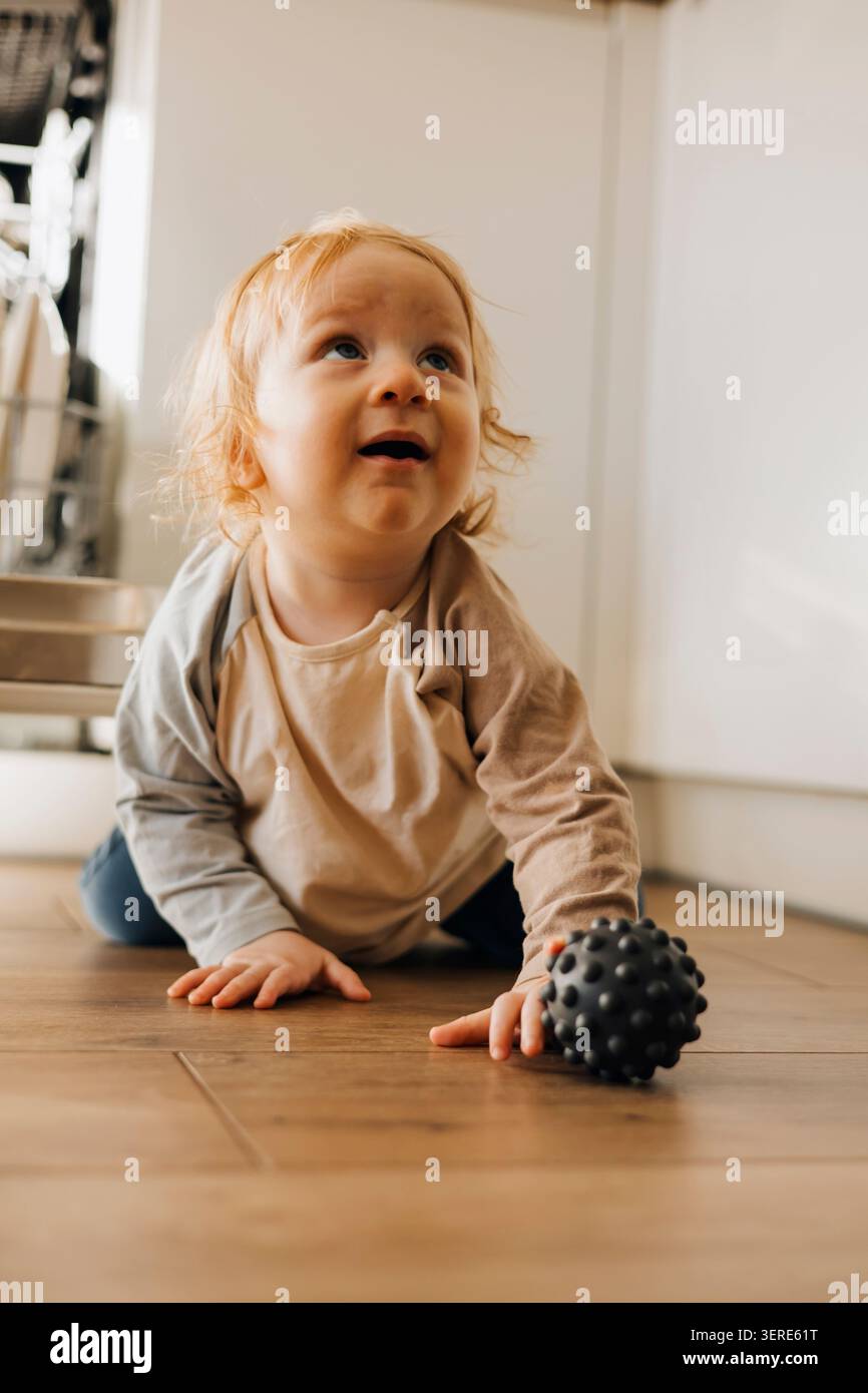 Curious Toddler Reaching for a Toy on the Kitchen Floor Stock Photo - Alamy