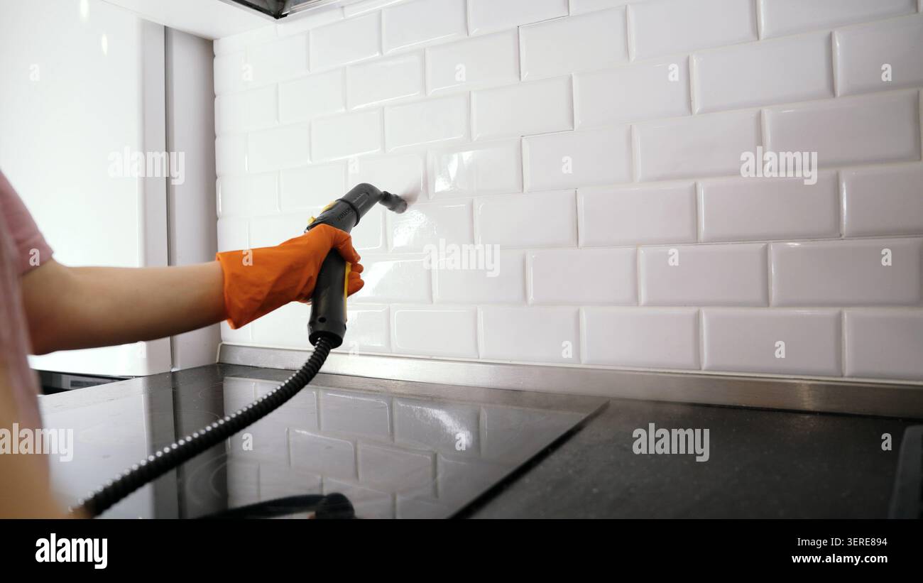 Person cleans white subway tile backsplash and black countertop using a ...