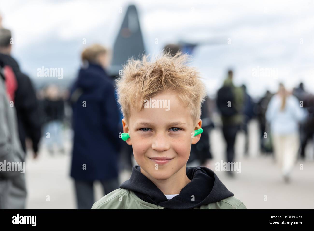 Portrait blond boy wear earplugs visiting aviation event crowd aircraft ...