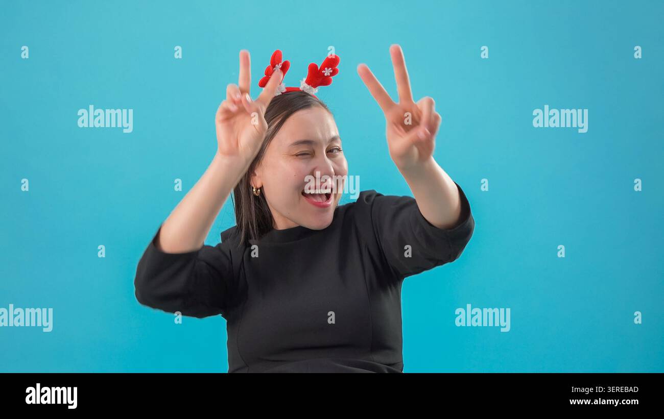 Woman with toy antlers gesturing on blue background Stock Photo - Alamy