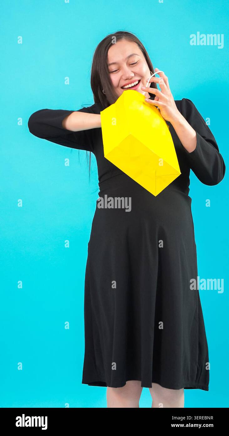 A woman holds up a yellow paper shape against a plain background Stock ...