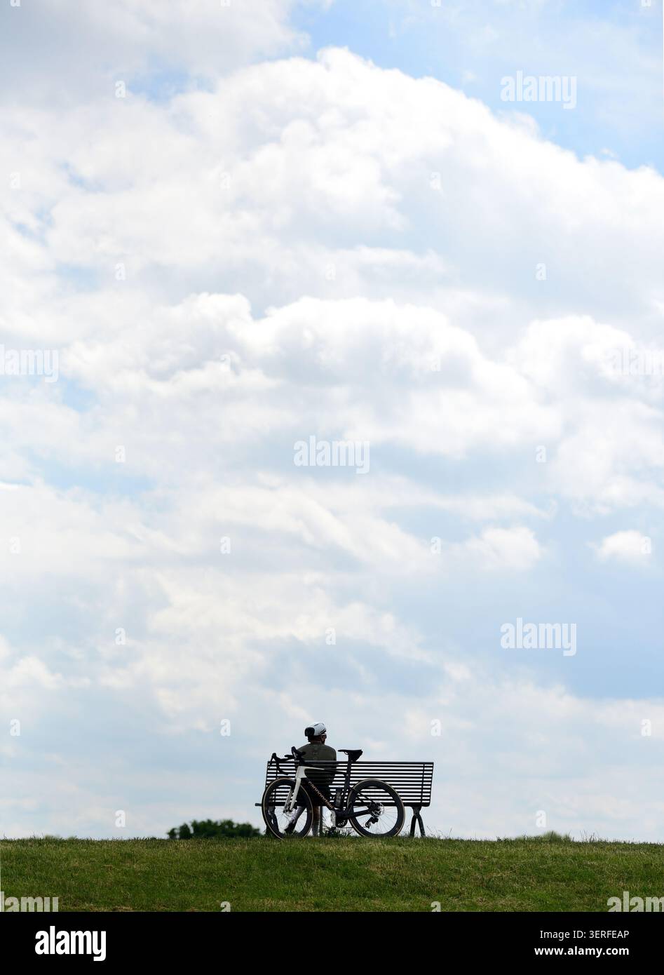 Hamburg, Germany. 18th Jun, 2026. A road cyclist is sitting on a bench ...