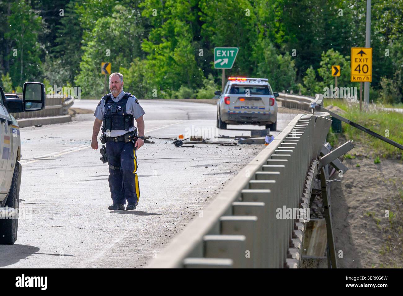 A police officer stands on the Wapiti River Bridge near a damaged ...
