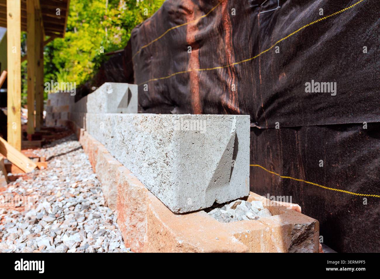 Workers are placing concrete blocks along building foundation ...