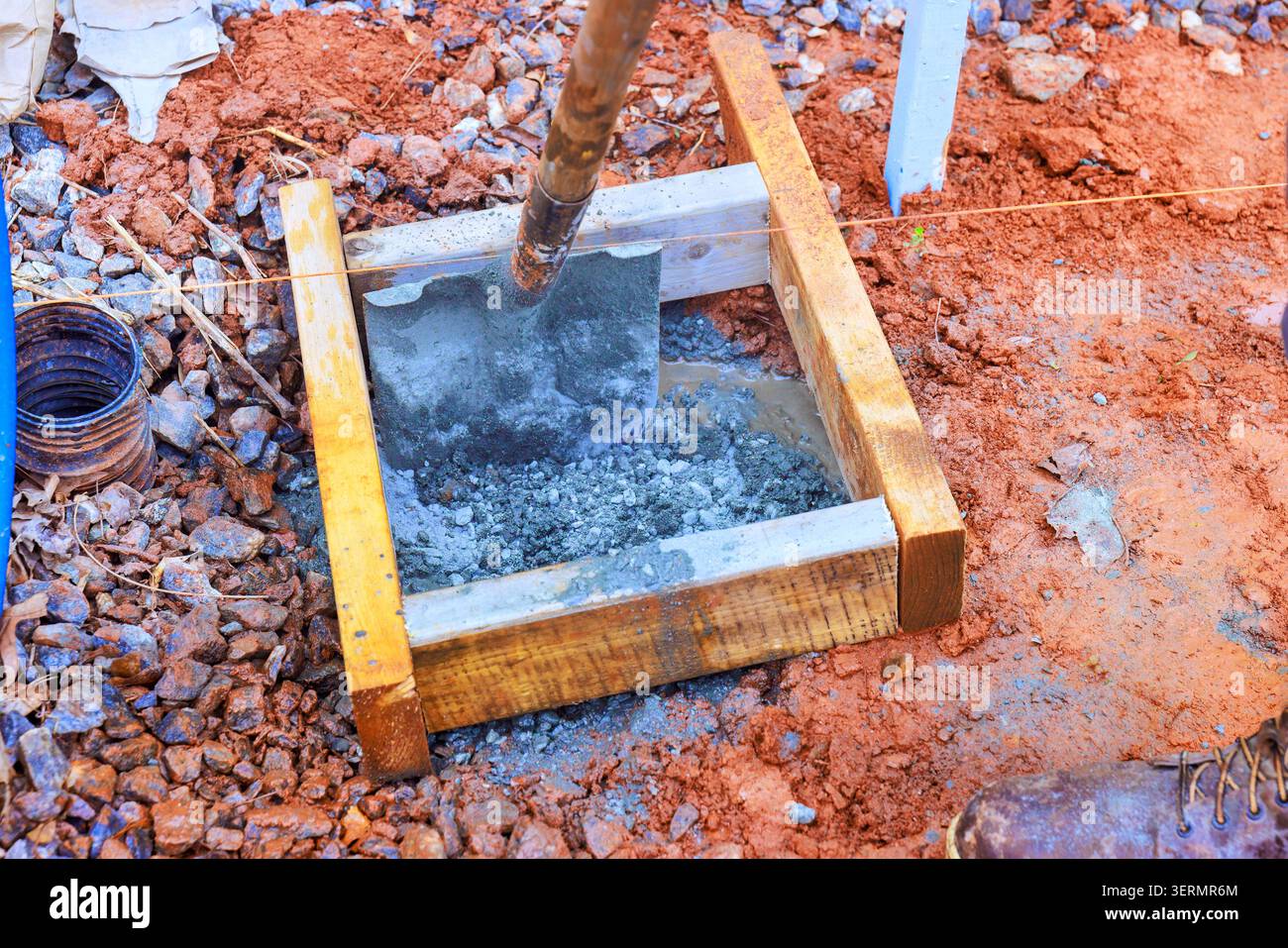 Workers set shovel in wet cement inside wooden frame at construction ...