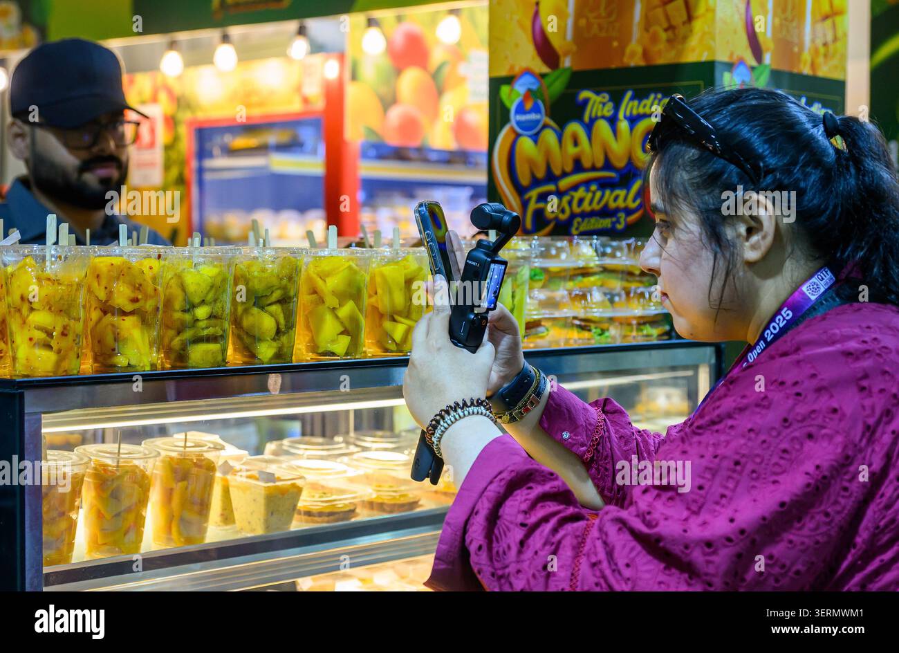 A woman takes a photo of mango products during the 3rd Indian Mango ...