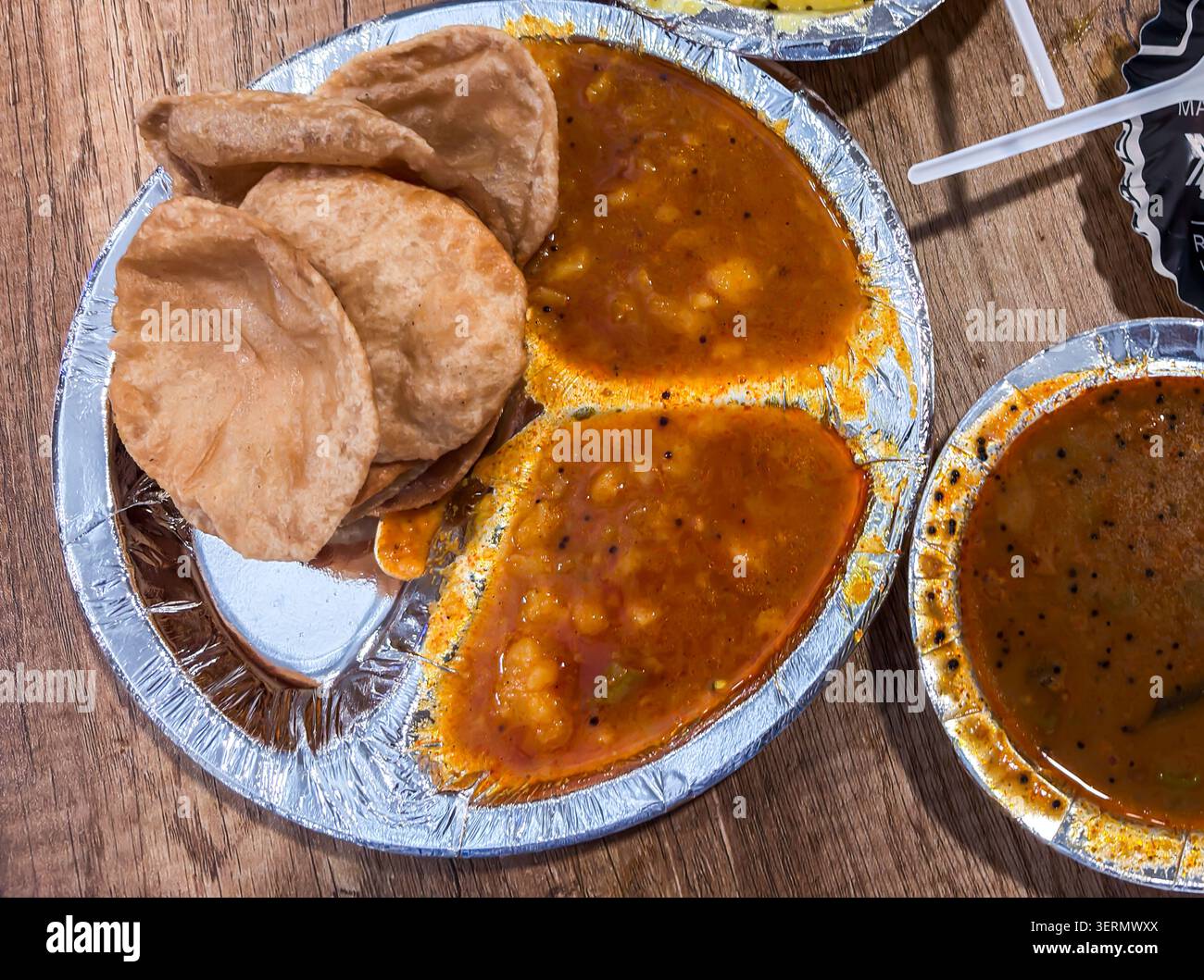crispy puri served with spicy chickpea curry on disposable plate over ...