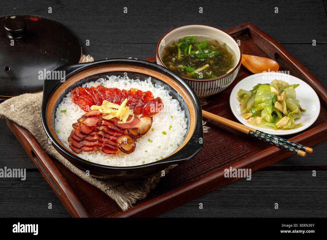 Chinese claypot rice with sliced Cantonese sausage on dark wooden table ...