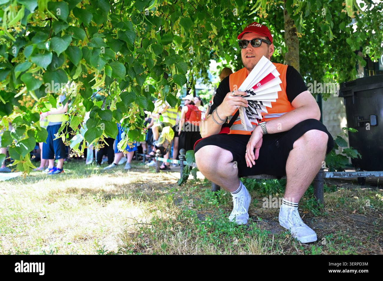 19 June 2026, Berlin: A man fans himself in the shade under a tree ...