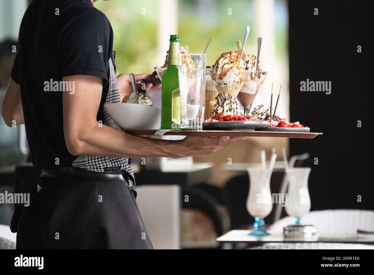 HANDOUT - 19 June 2026, Saxony, Dresden: A waitress carries ice cream ...