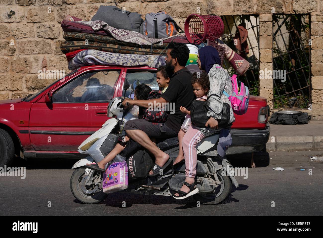 A displaced family on a scooter fleeing Israeli strikes in southern ...