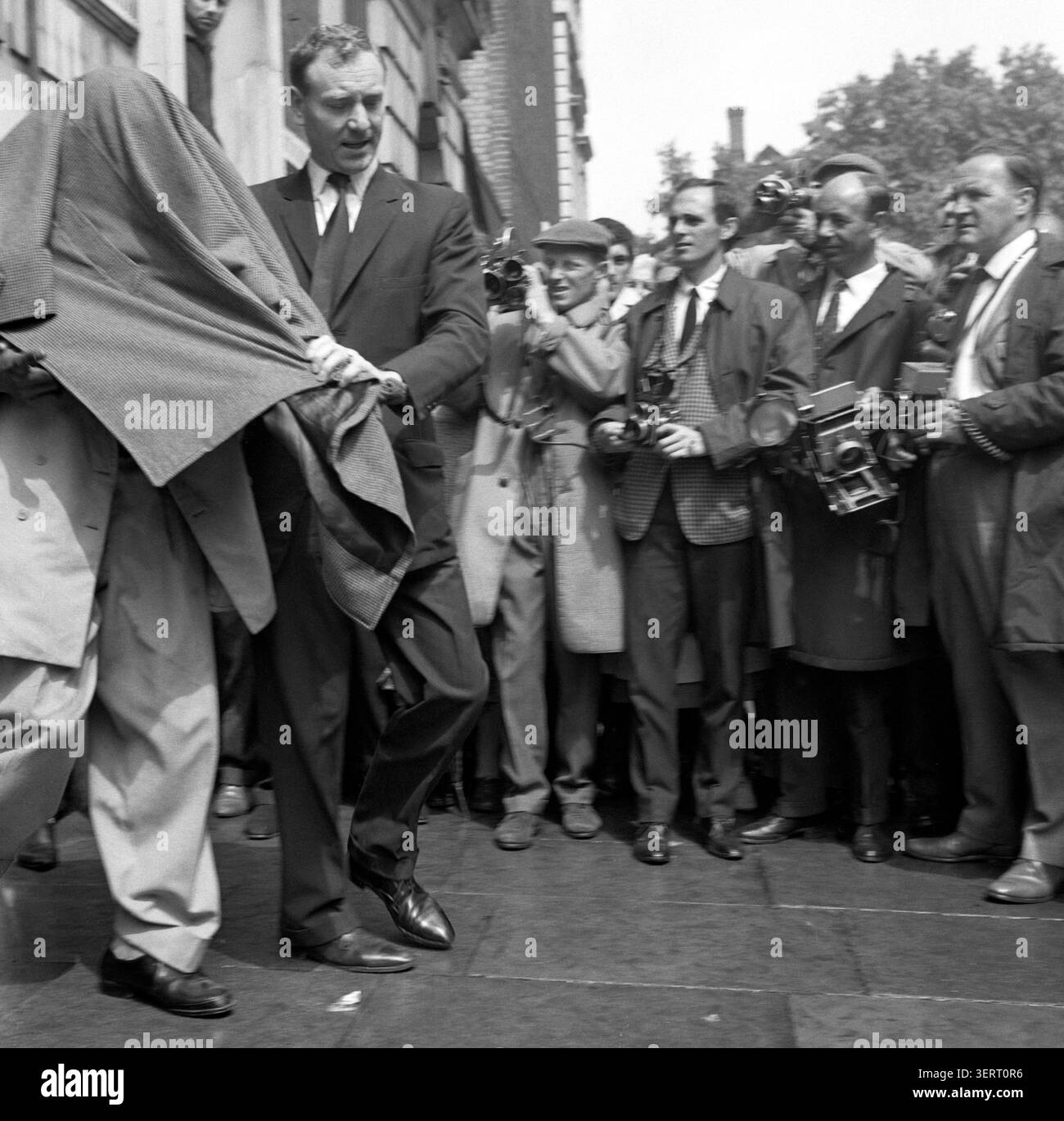 A man leaves Marylebone Magistrates Court with a coat over his head, on ...