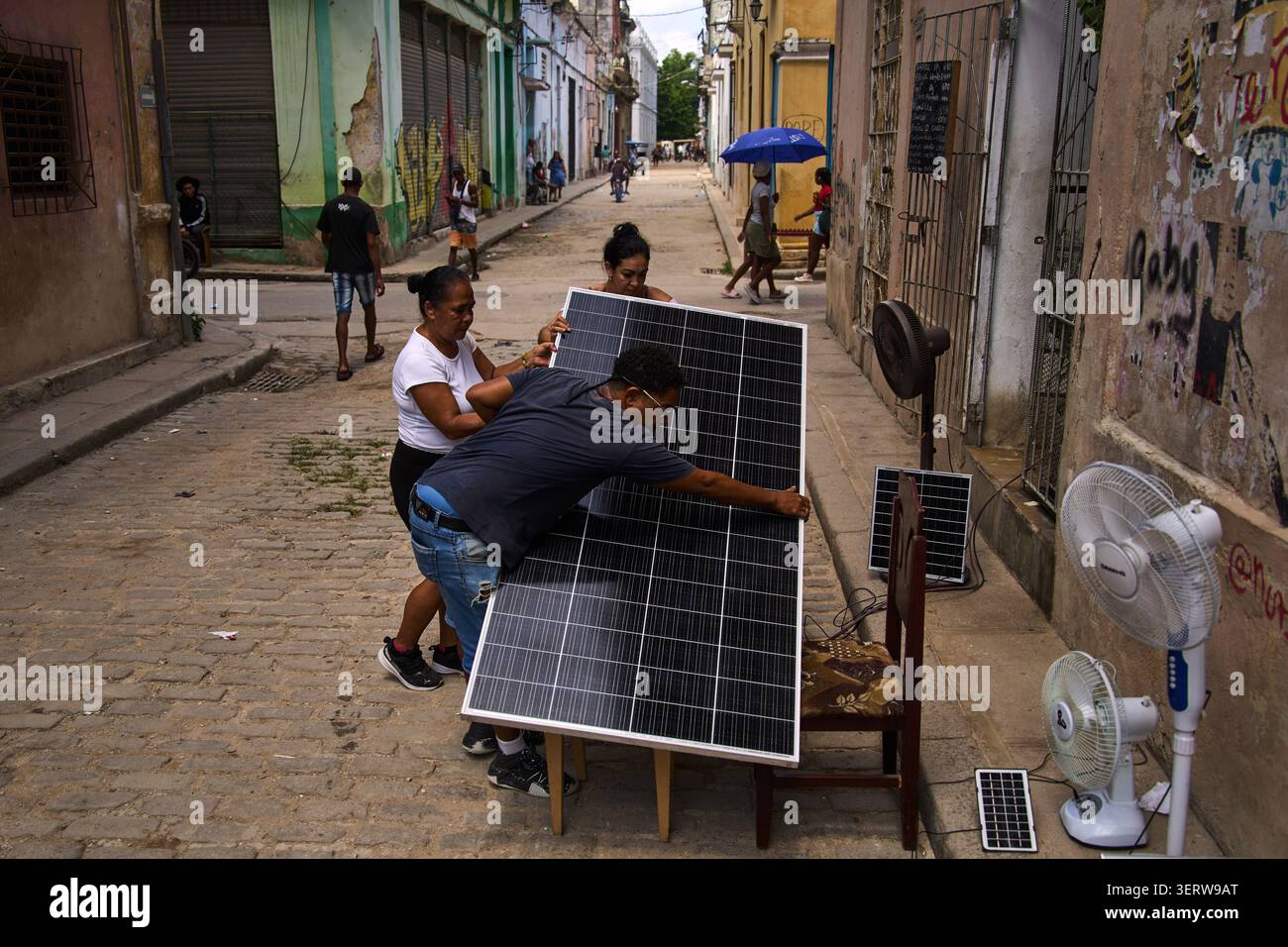 People prepare solar panels set up on the street to charge batteries ...