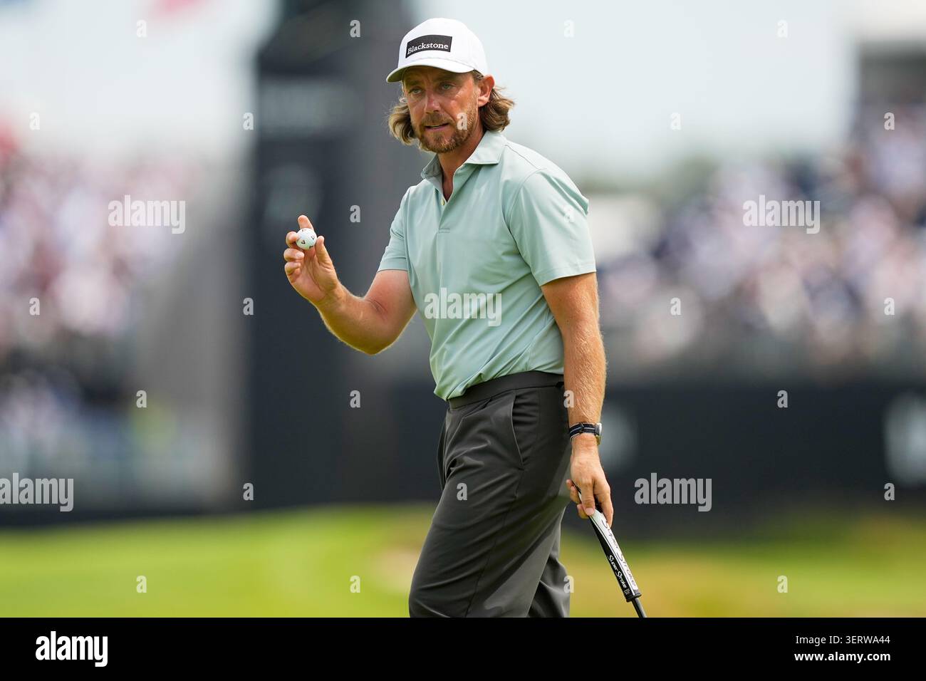Tommy Fleetwood, of England, waves after his putt on the third hole ...