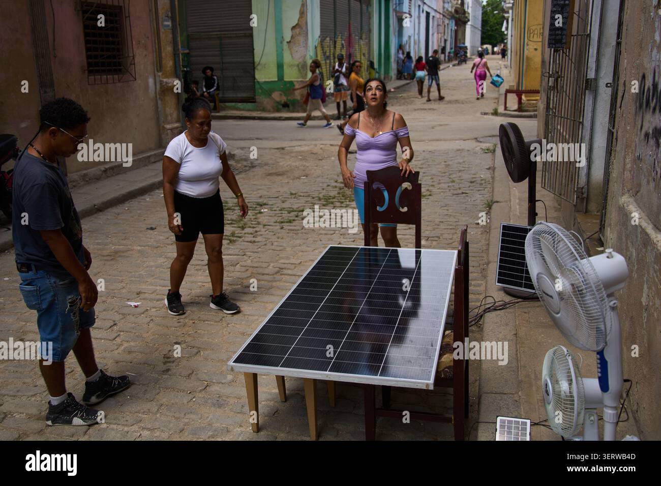 People prepare solar panels set up on the street to charge batteries ...