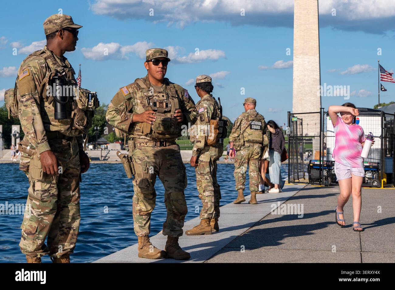 A girl looks at National Guard who are standing watch in front of paint ...