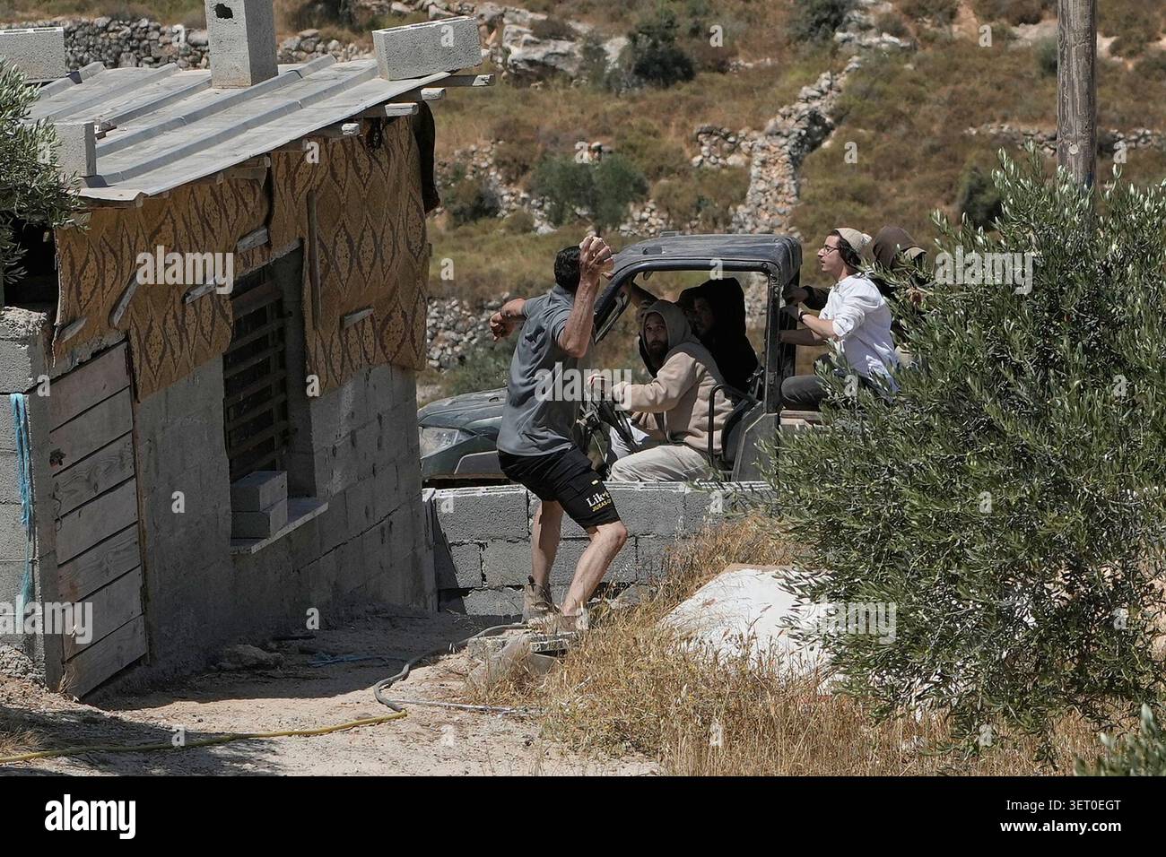 A Palestinian villager throws stones at Israeli settlers during clashes ...