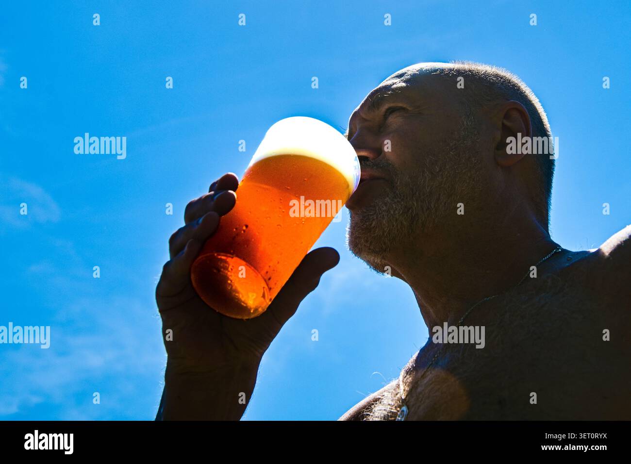 Man drinks a beer at the Zatoka swimming pool on a hot summer day, on ...