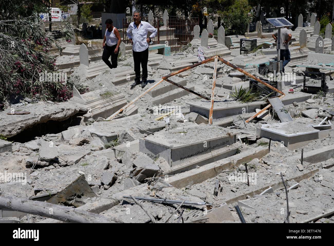 People inspect a damaged cemetery near the site of destroyed buildings ...