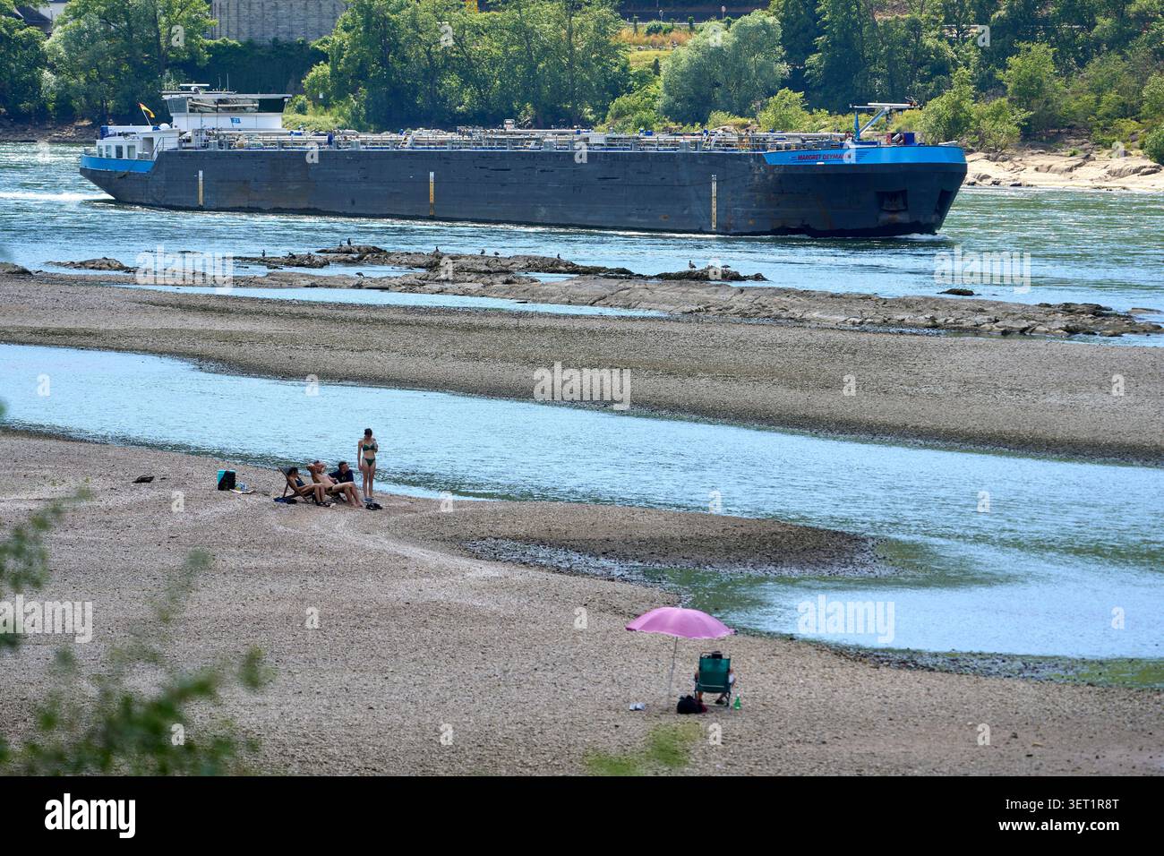 People visit the banks of the Rhine near the Loreley as a cargo ship ...