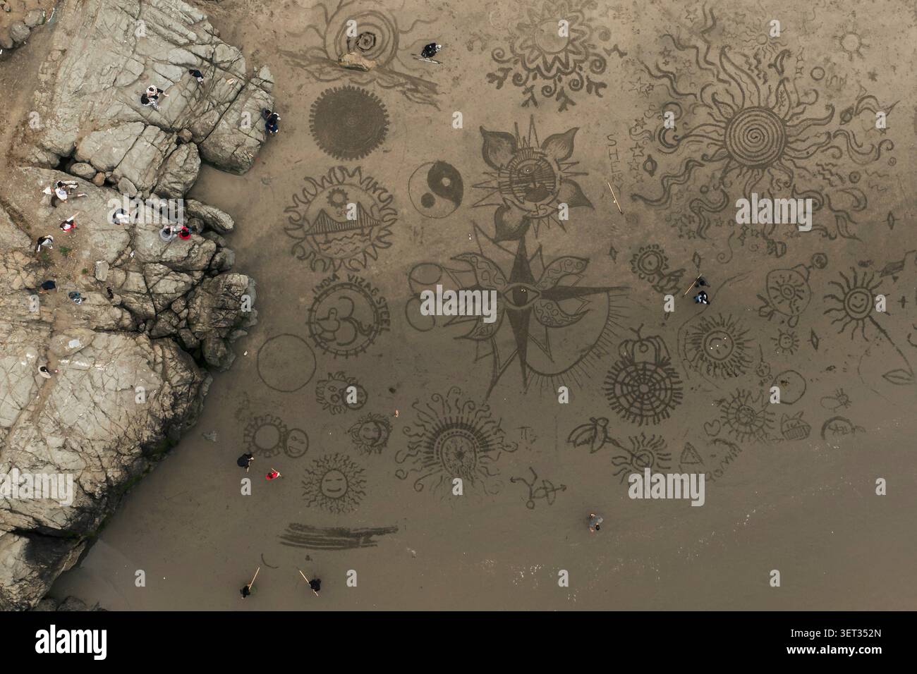 Participants gather to create artwork in the sand at Ocean Beach during ...