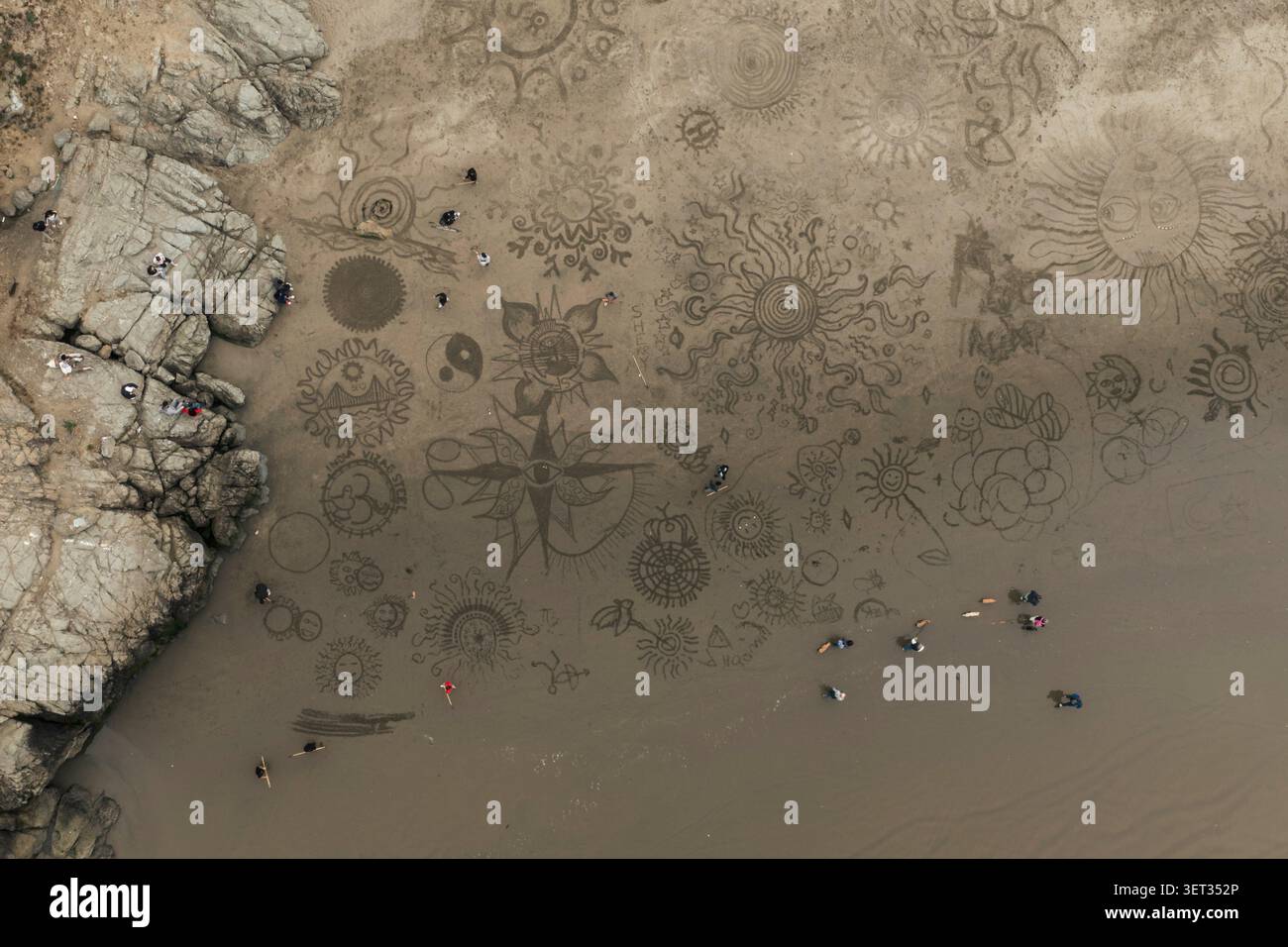 Participants gather to create artwork in the sand at Ocean Beach during ...