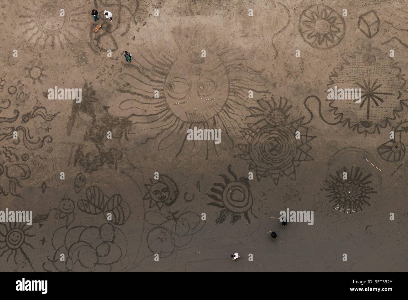 Participants gather to create artwork in the sand at Ocean Beach during ...