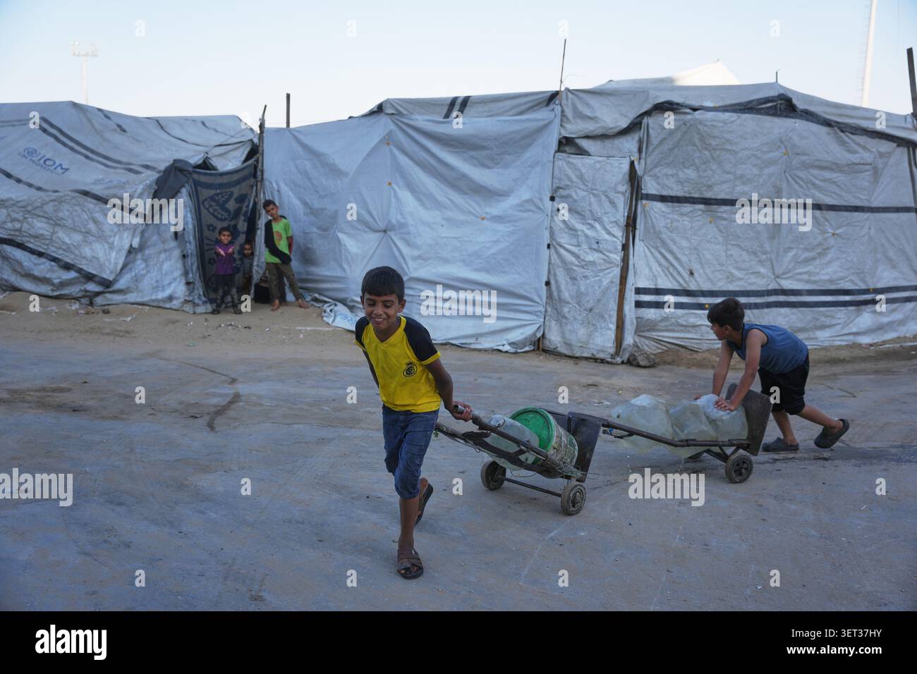 Displaced Palestinian children haul water containers at the Yarmouk ...