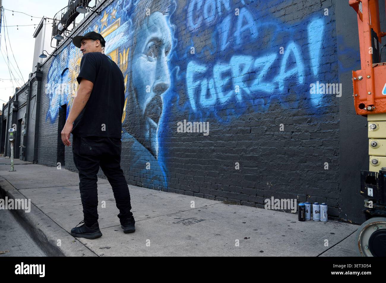 Artist Jose May, aka Joe Skilz, stands near his mural of Argentina star ...