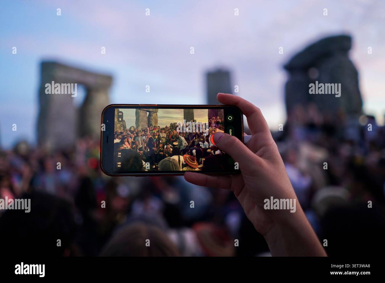 A reveler makers a video with a phone at the ancient stone circle ...