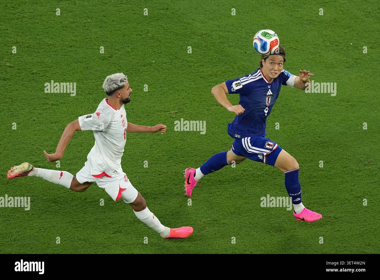 Japan's Kou Itakura heads the ball chased by Tunisia's Elias Saad ...