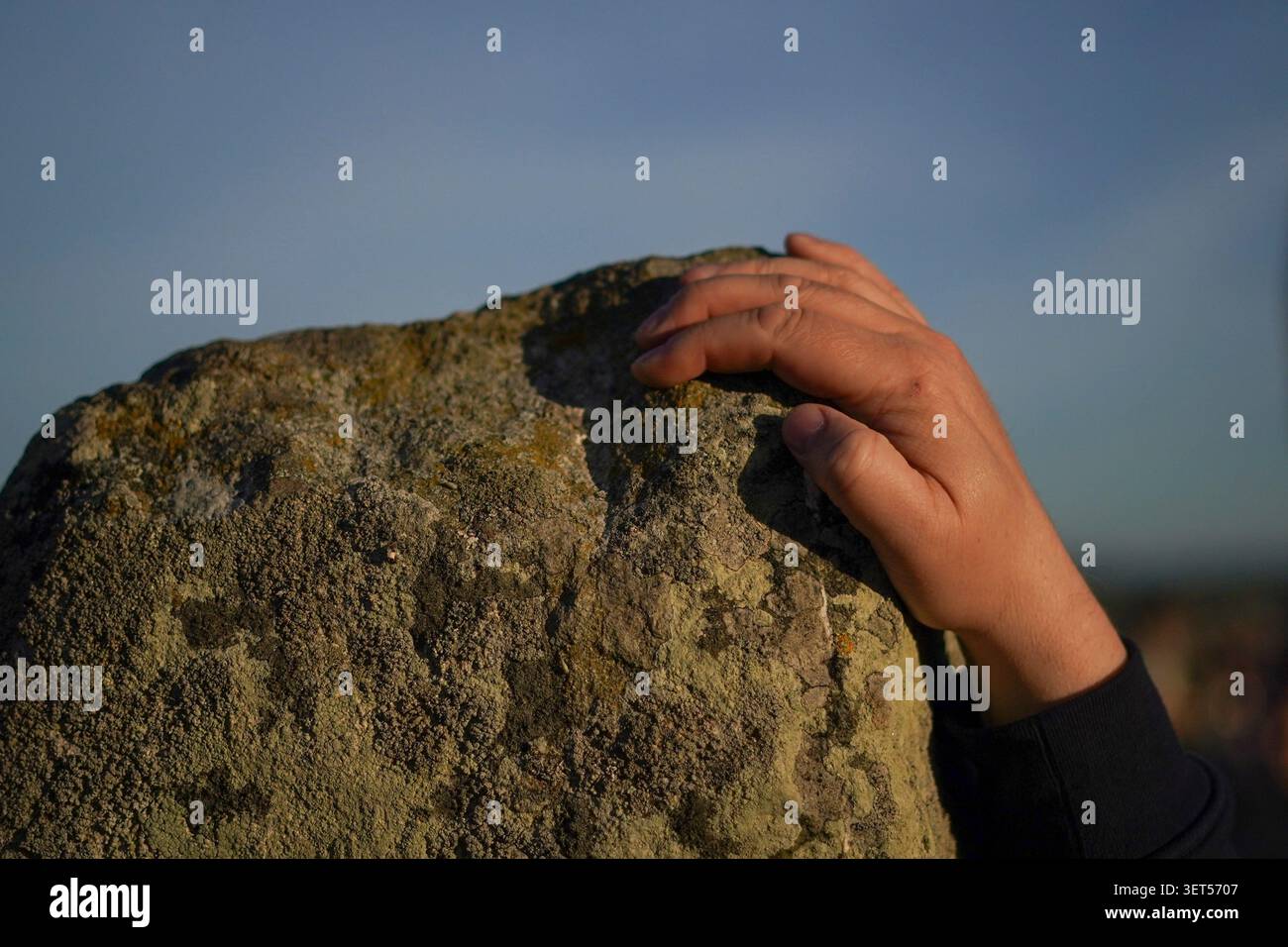 A reveler touches a stone at the ancient stone circle Stonehenge at ...