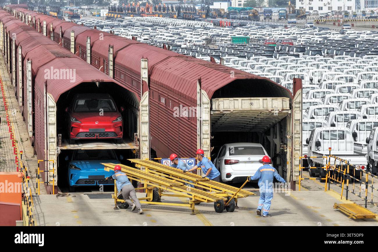Workers prepare to load cars off a freight train at a dock for ...