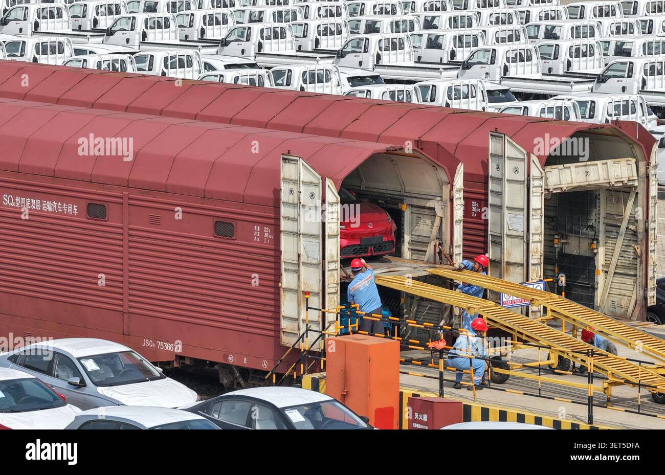 Workers prepare to load cars off a freight train at a dock for ...