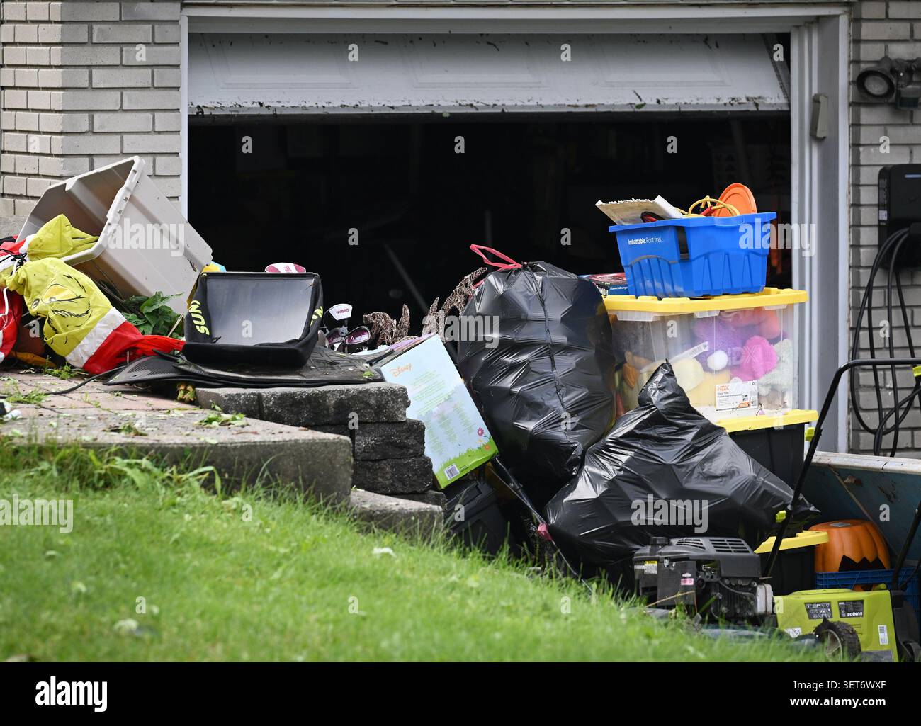 Bags and boxes of belongings are shown on the lawn of a flooded home in ...