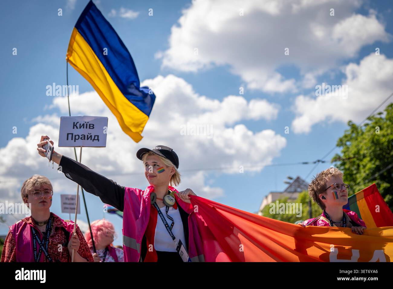 A participant takes a selfie whilst holding a sign reading 'Kyiv Pride ...