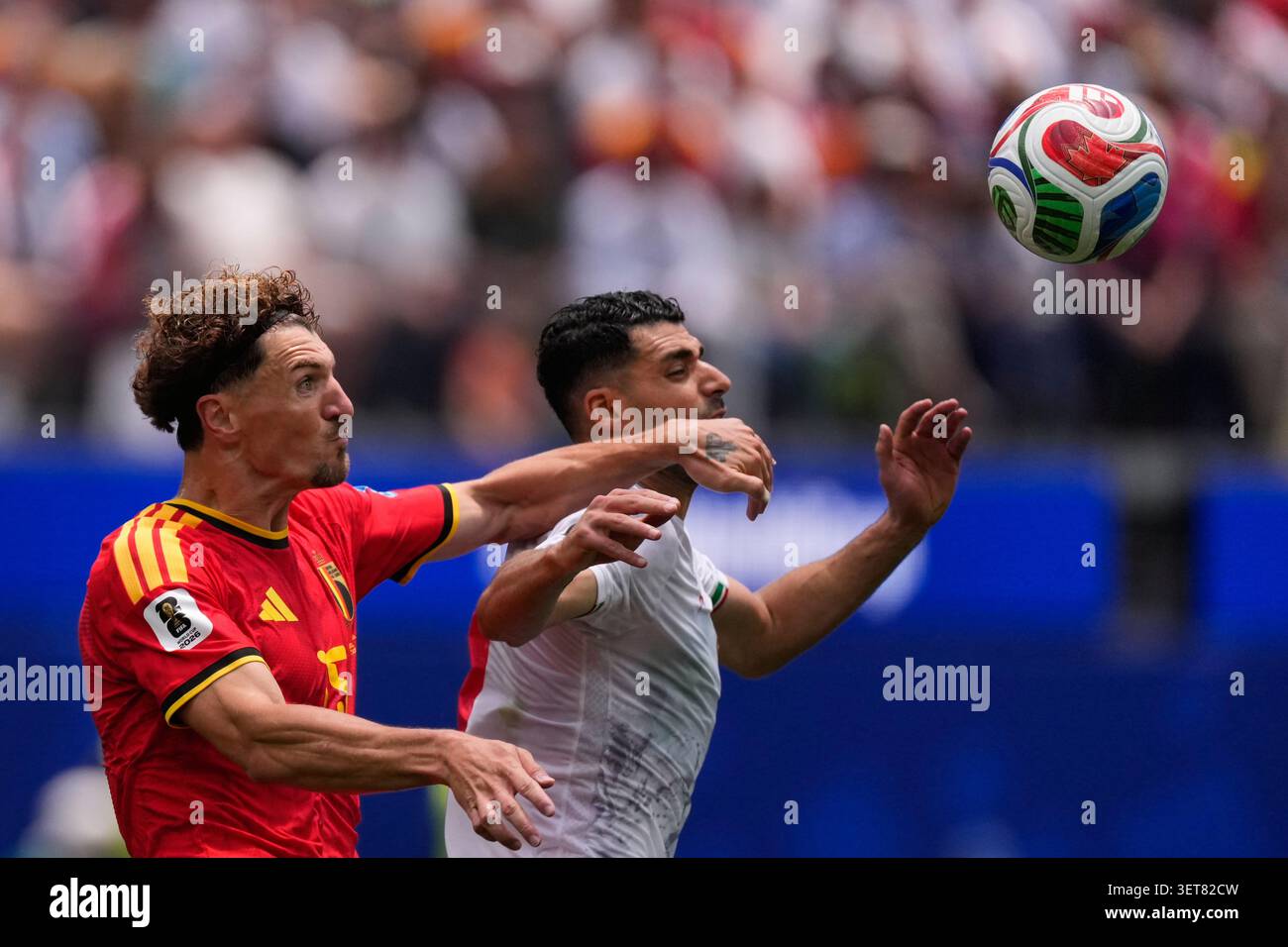 Belgium's Thomas Meunier, left, and Iran's Mehdi Taremi view the ball ...