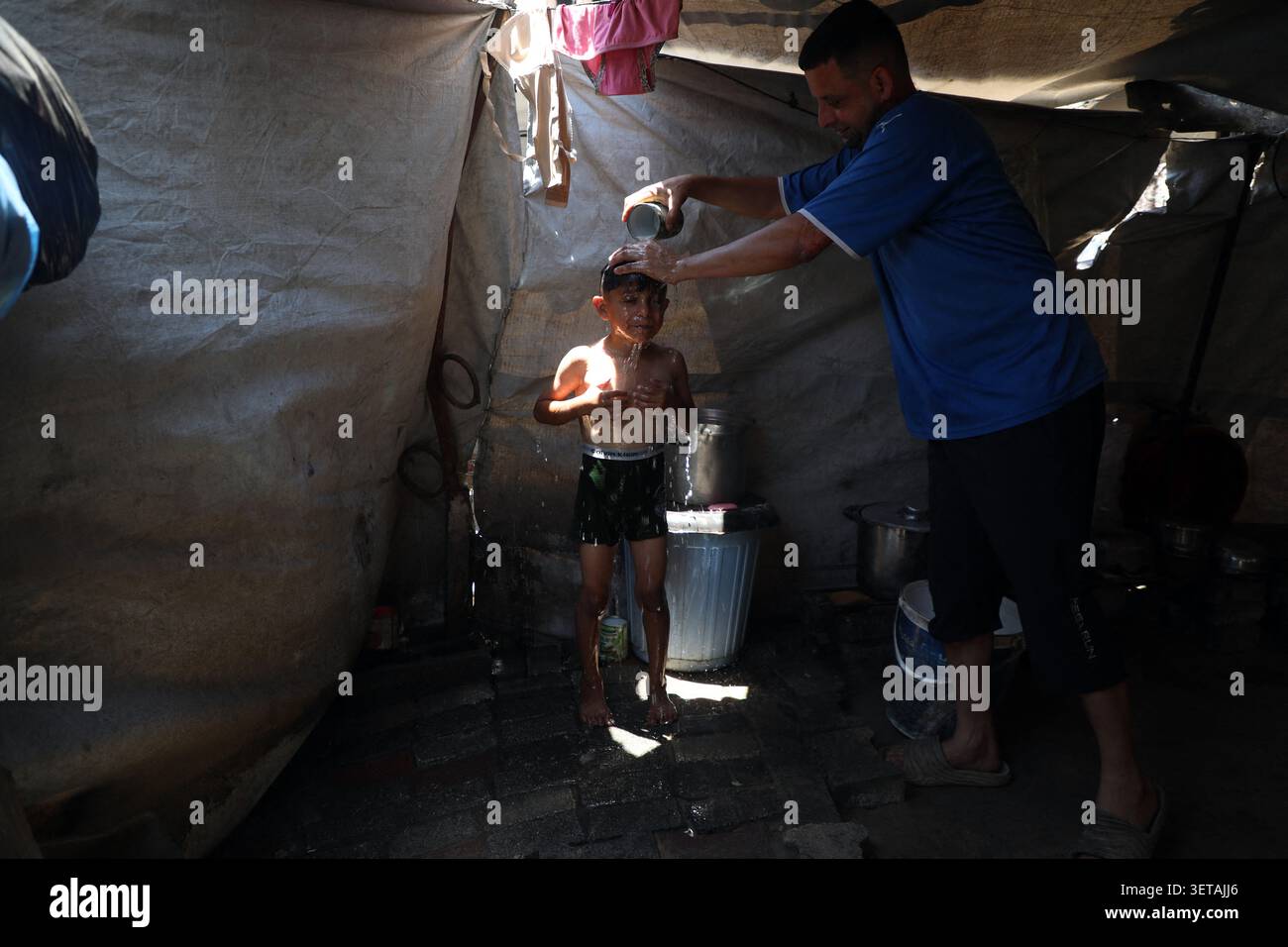 Palestinian children bathe in their tent inside a displacement camp in ...