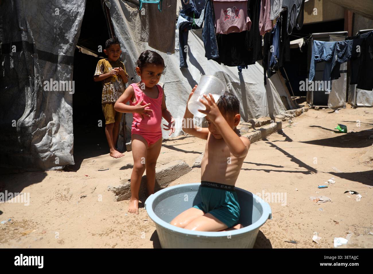 Palestinian children bathe in their tent inside a displacement camp in ...