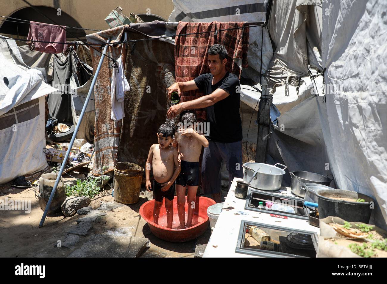 Palestinian children bathe in their tent inside a displacement camp in ...