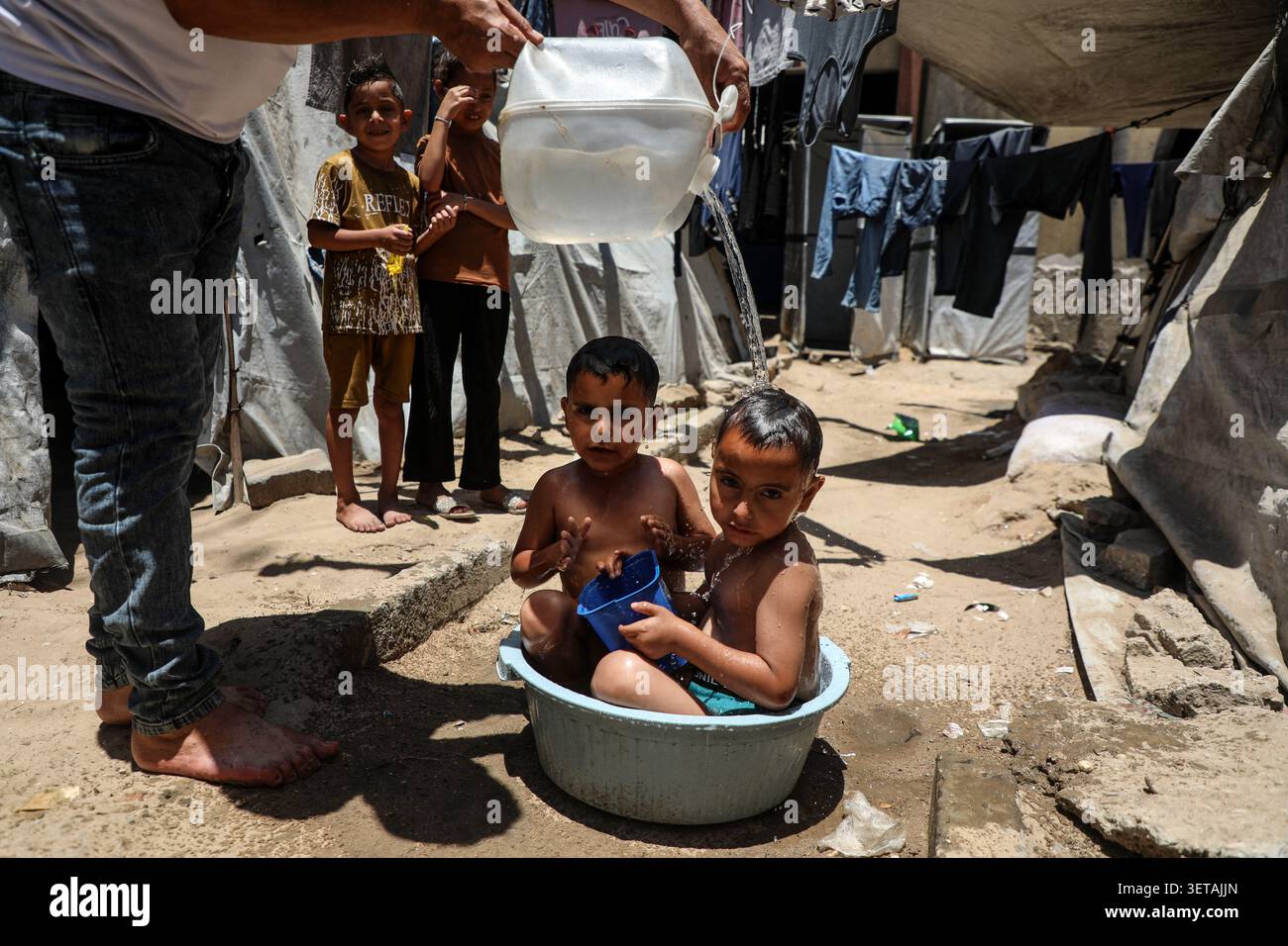 Palestinian children bathe in their tent inside a displacement camp in ...